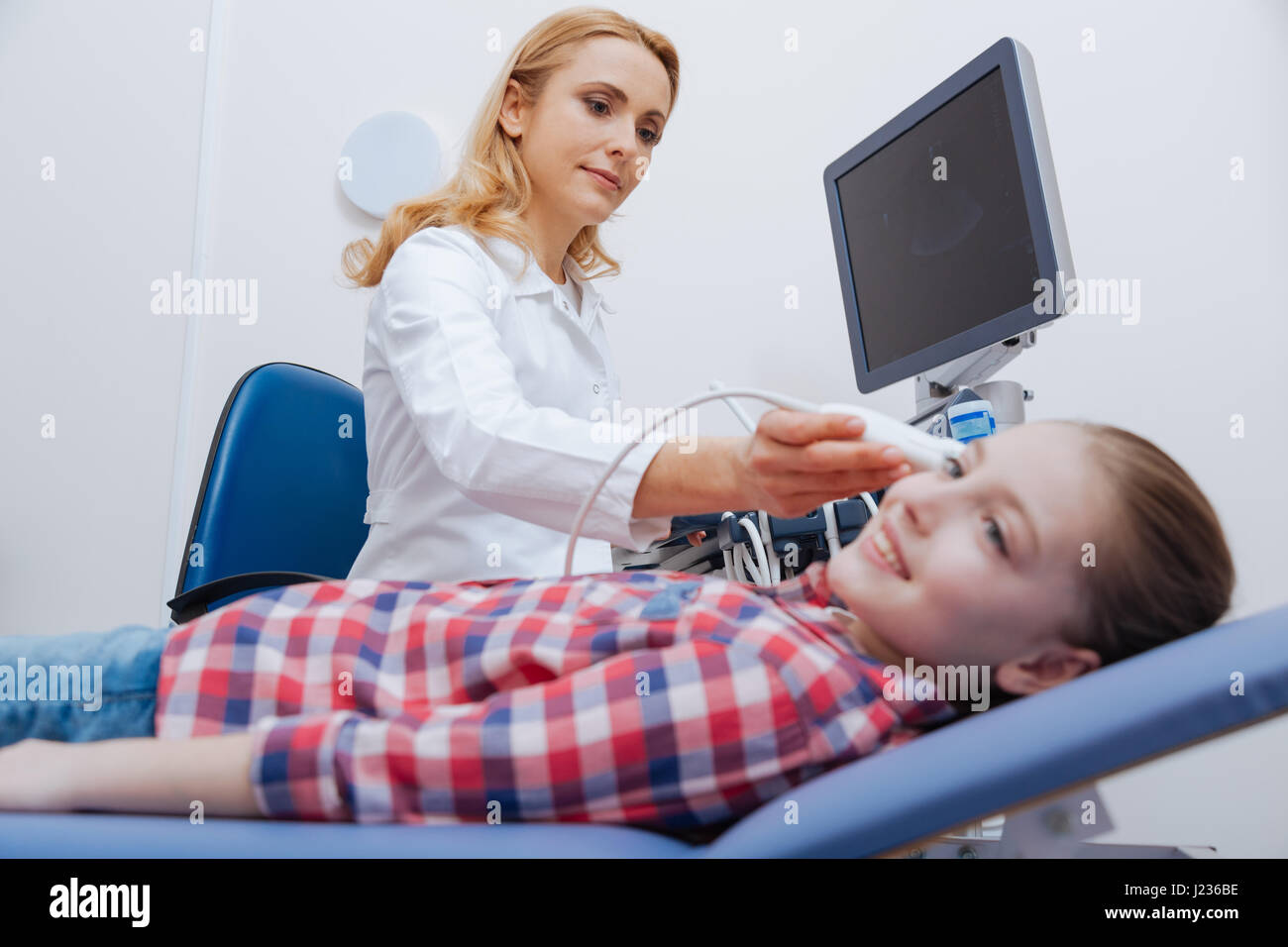 Smiling little girl getting ultrasonic head scanning in the clinic ...