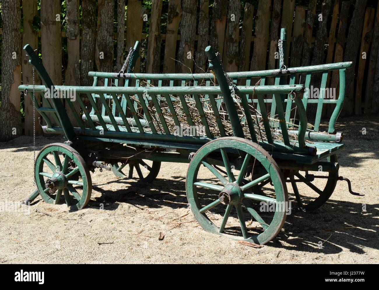 Old wooden green farm wagon with wooden fence as background in bright ...