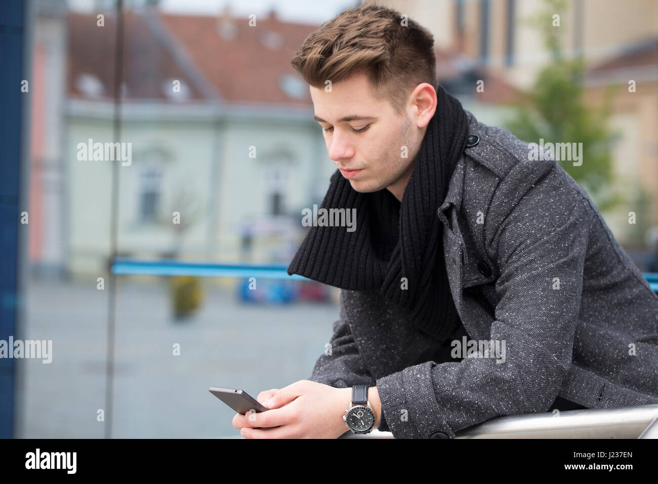 Handsome attractive young man holding a mobile phone in hand , typing ...