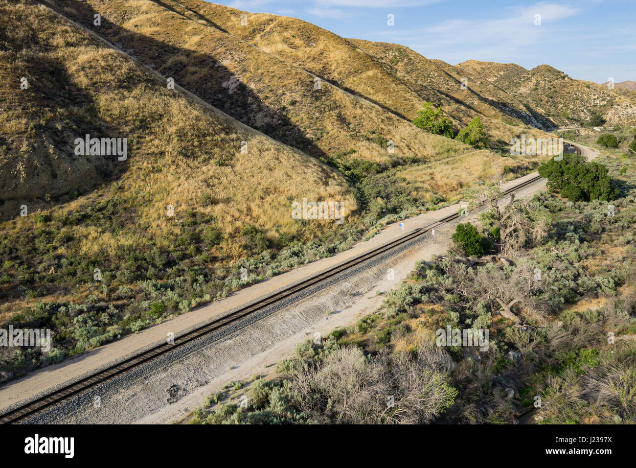 Railroad track line along the bottom of desert foothills in California ...