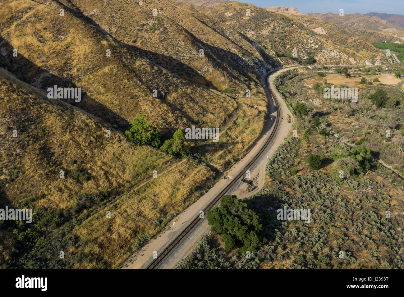 Bending winding railroad tracks lies through the desert hills of ...