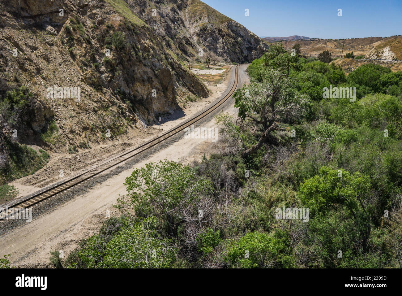 Railroad track runs through California canyon near a running stream ...