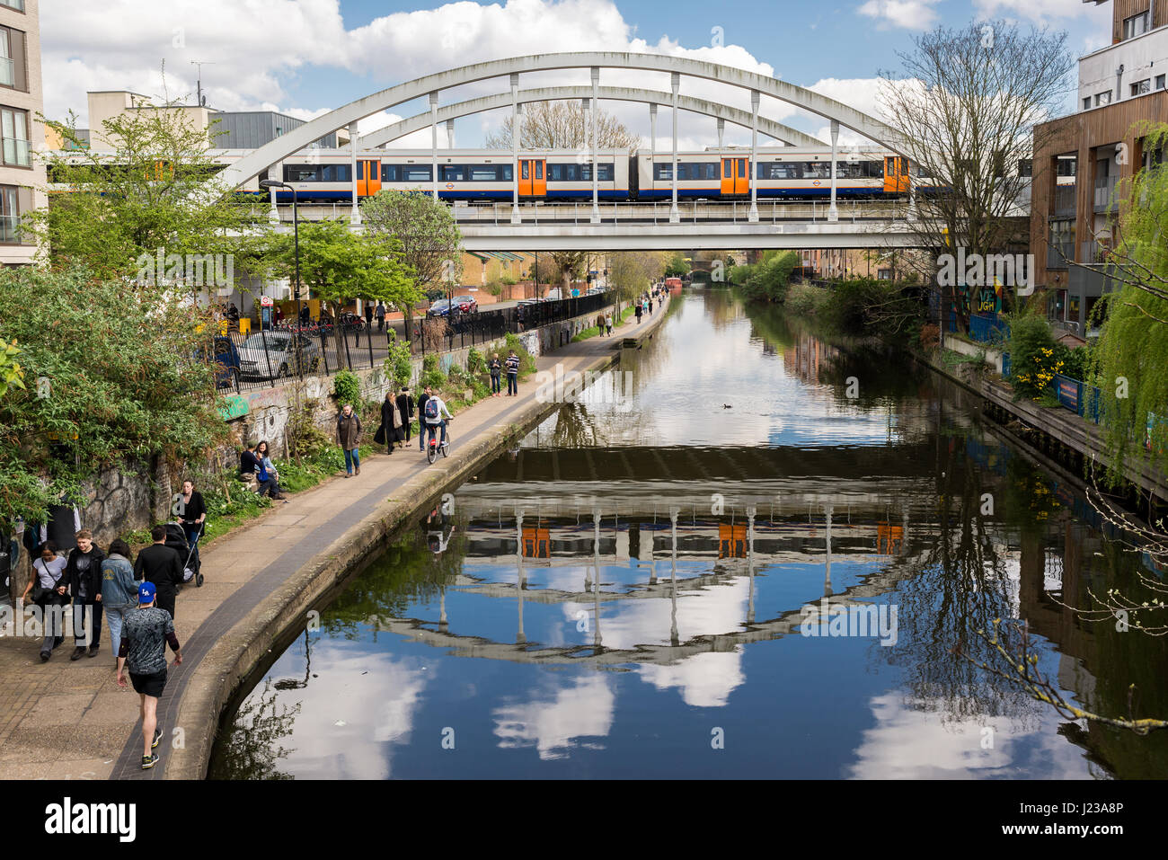 Overground train crossing the Regent's Canal at Haggerston with people ...