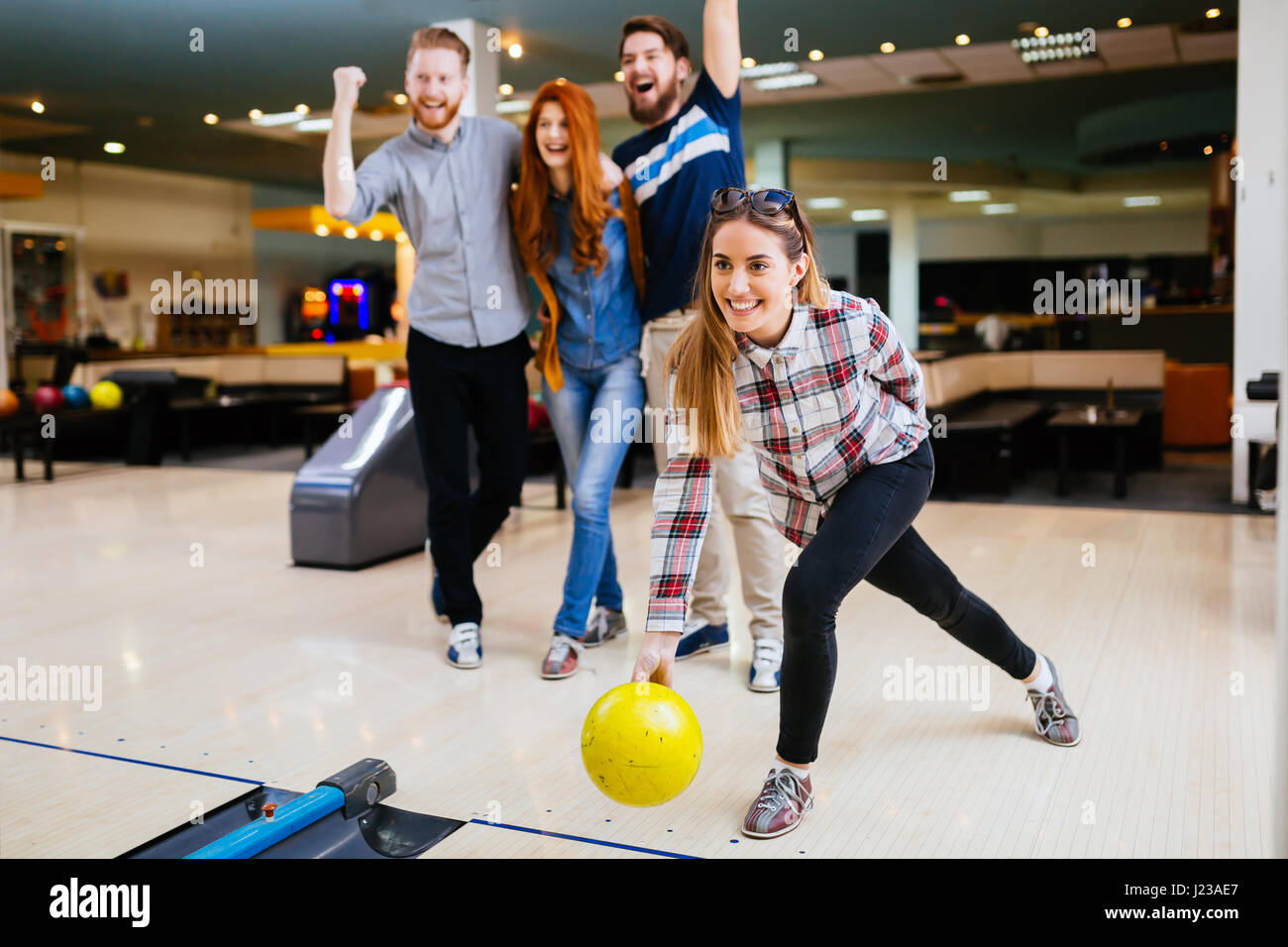 Friends enjoying competitive bowling Stock Photo - Alamy