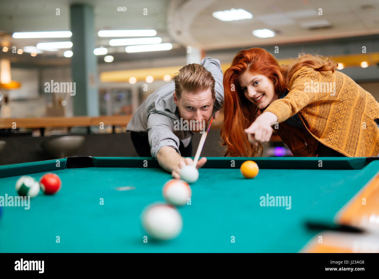 Beautiful happy couple playing billiards Stock Photo - Alamy