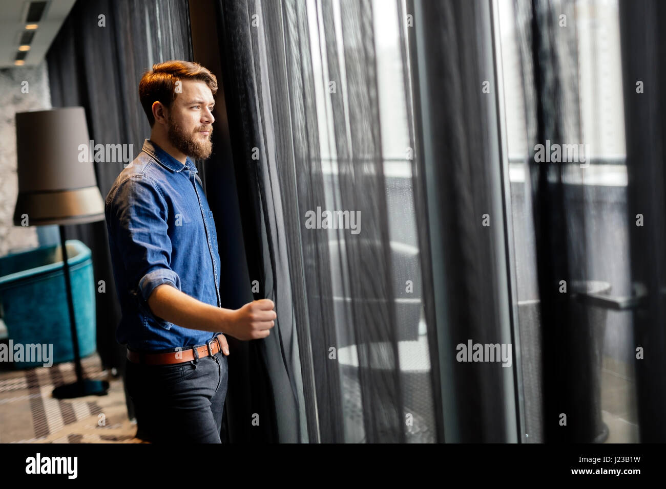 Handsome man looking at cityscape through skyscraper window Stock Photo ...