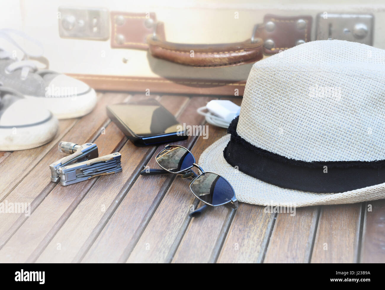 straw hat, sunglasses, phone shoes and suitcase on wooden background ...