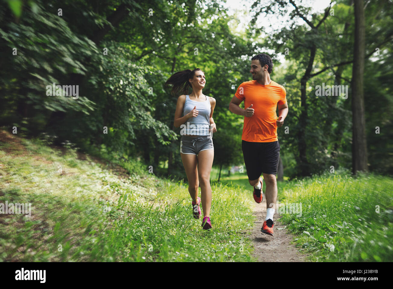 Happy couple running and jogging together in nature Stock Photo - Alamy