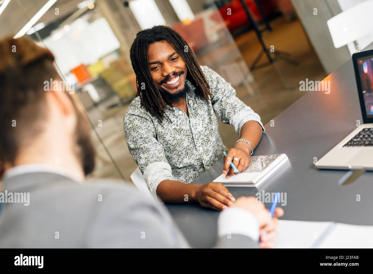 Black handsome employee smiling in office Stock Photo - Alamy