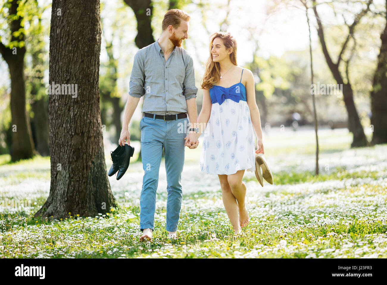 Couple enjoying romantic walk in nature barefoot Stock Photo - Alamy