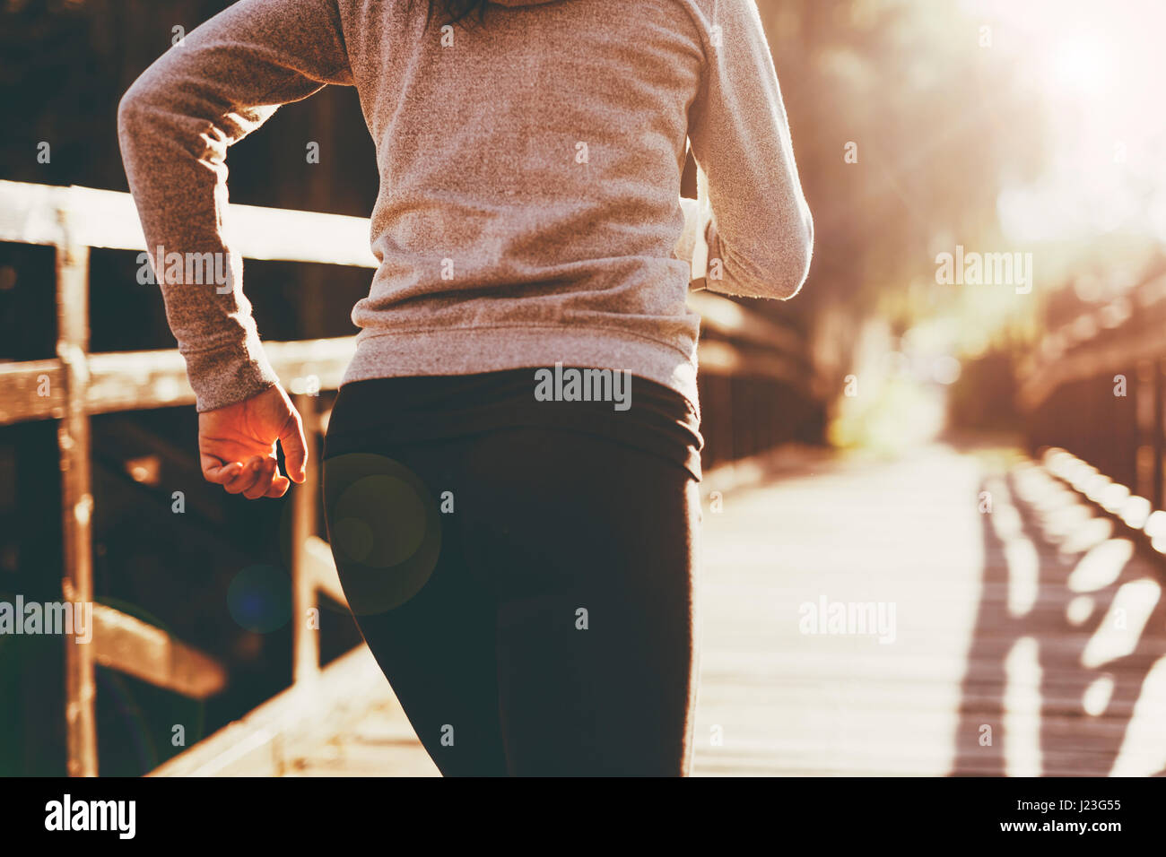 Female jogger running in beautiful sunset with a nice flare showing on ...