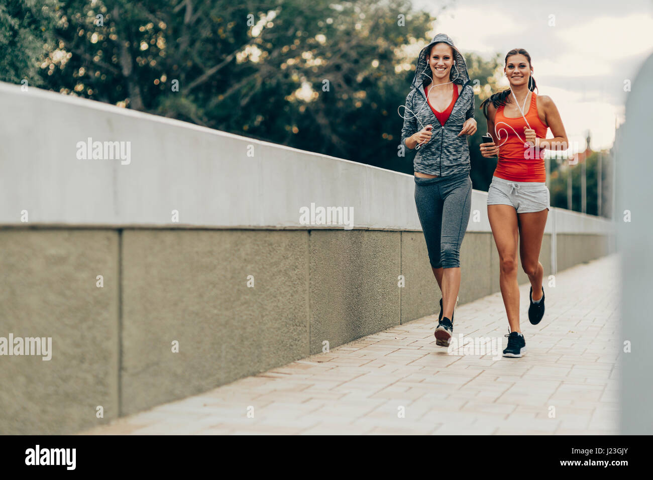 Beautiful women jogging in city while sun is setting down Stock Photo ...