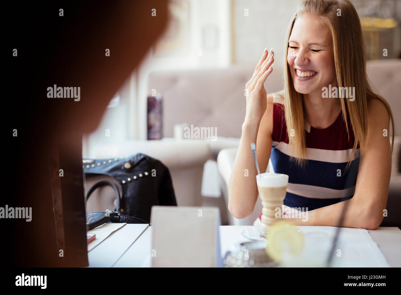 Beautiful women smiling in restaurant and cracking jokes Stock Photo ...