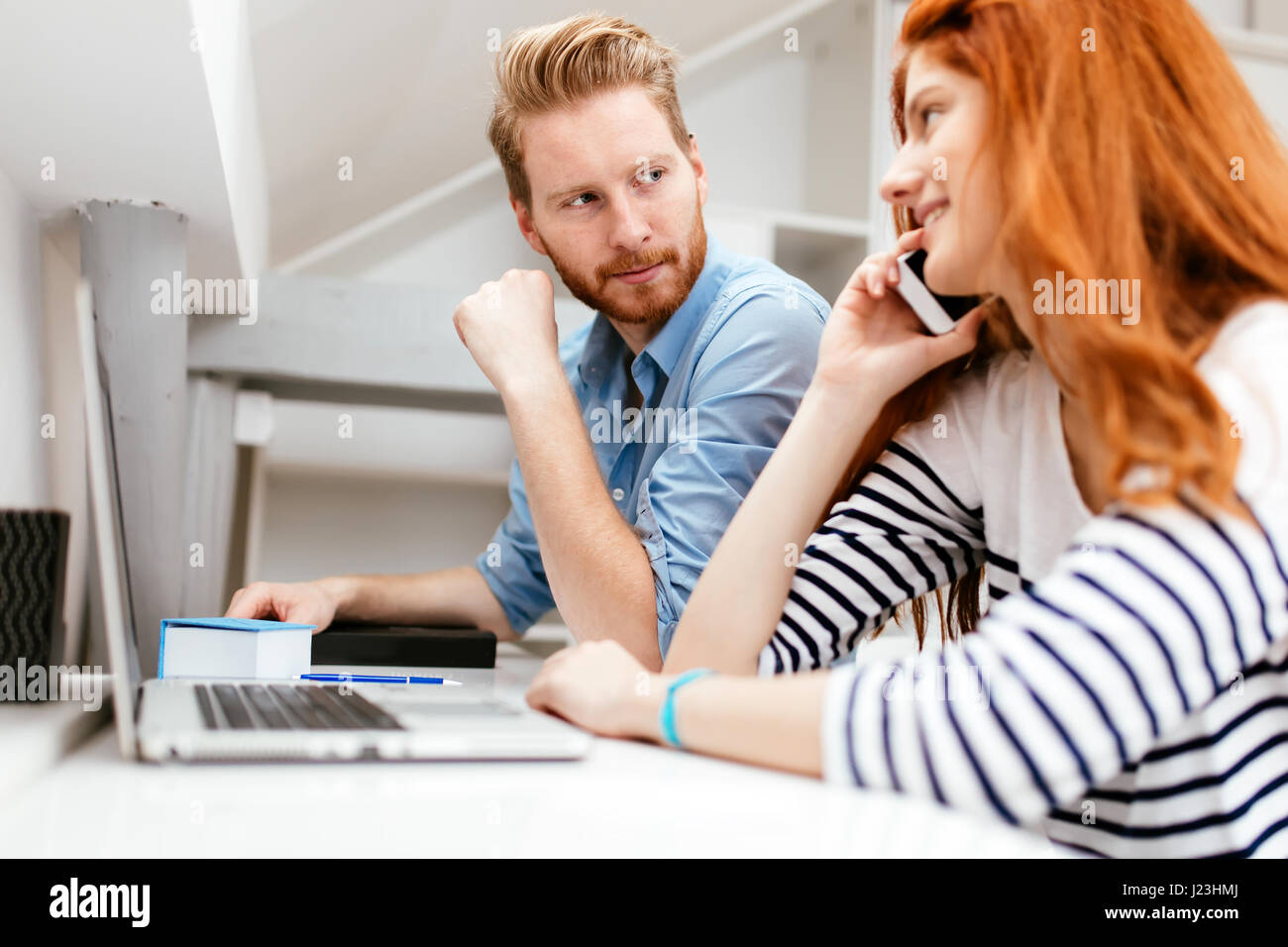 Woman calling partner from office with colleague sitting next to her ...
