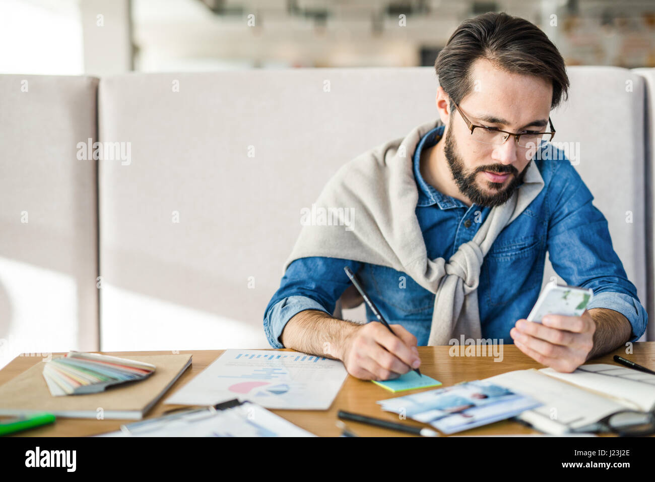 Serious economist with smartphone searching for data in the net Stock ...