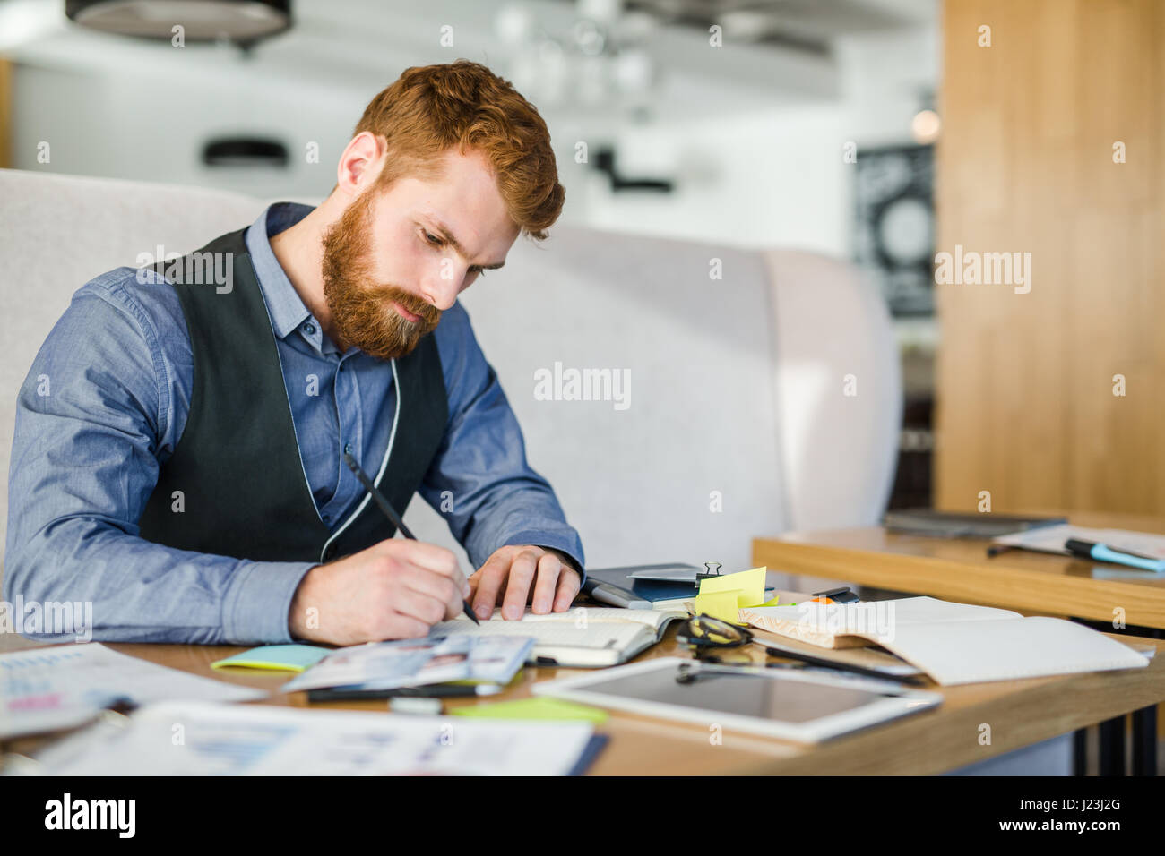 Young man making notes in notebook after analyzing data Stock Photo - Alamy