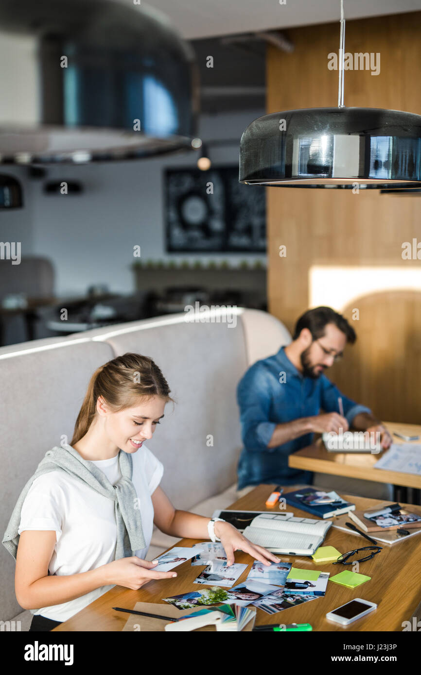 Happy girl looking through photos while working in cafe Stock Photo - Alamy