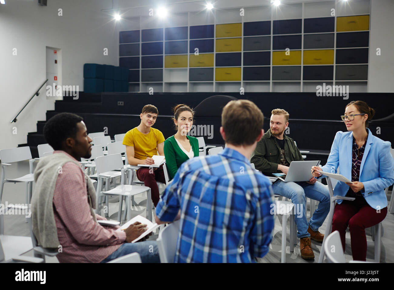 Group of students having talk in lecture hall Stock Photo - Alamy