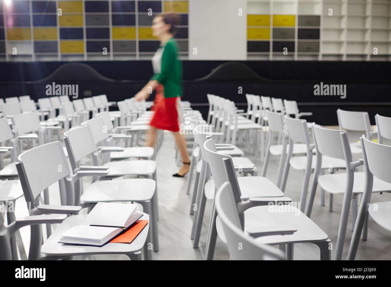 Businesswoman moving in aisle of conference hall between chairs Stock ...
