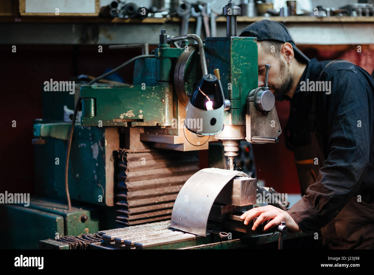 Portrait of man in workers uniform using drilling unit to make metal ...