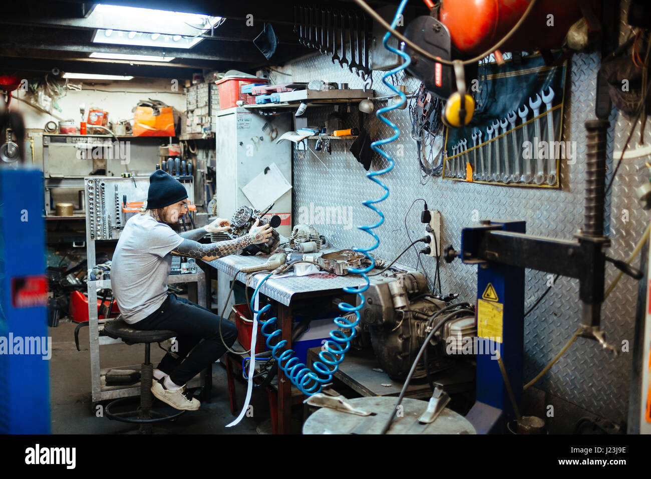 Side view portrait of modern tattooed man inspecting broken engine ...