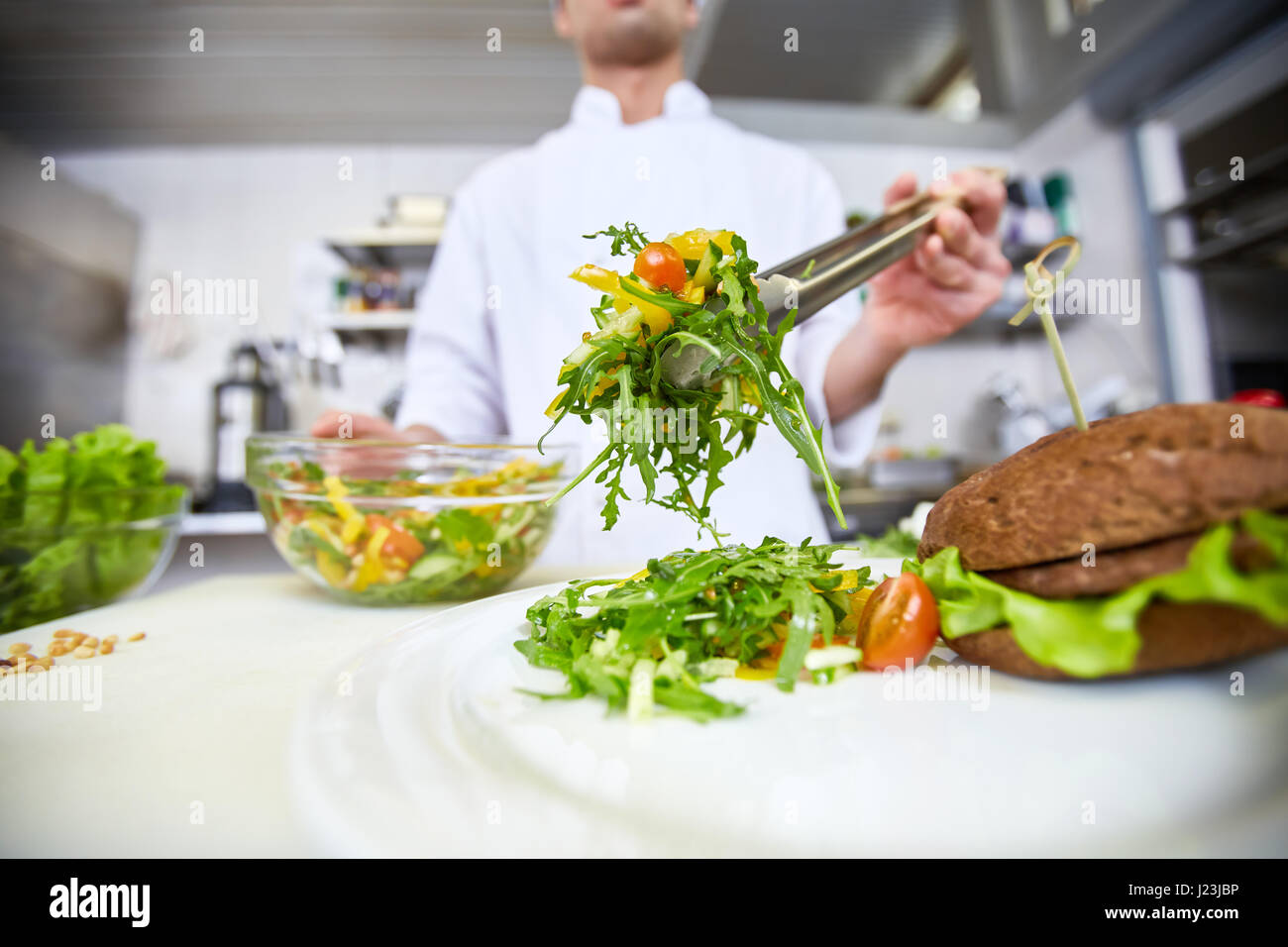 Chef putting fresh vegetable salad on plate for client Stock Photo - Alamy