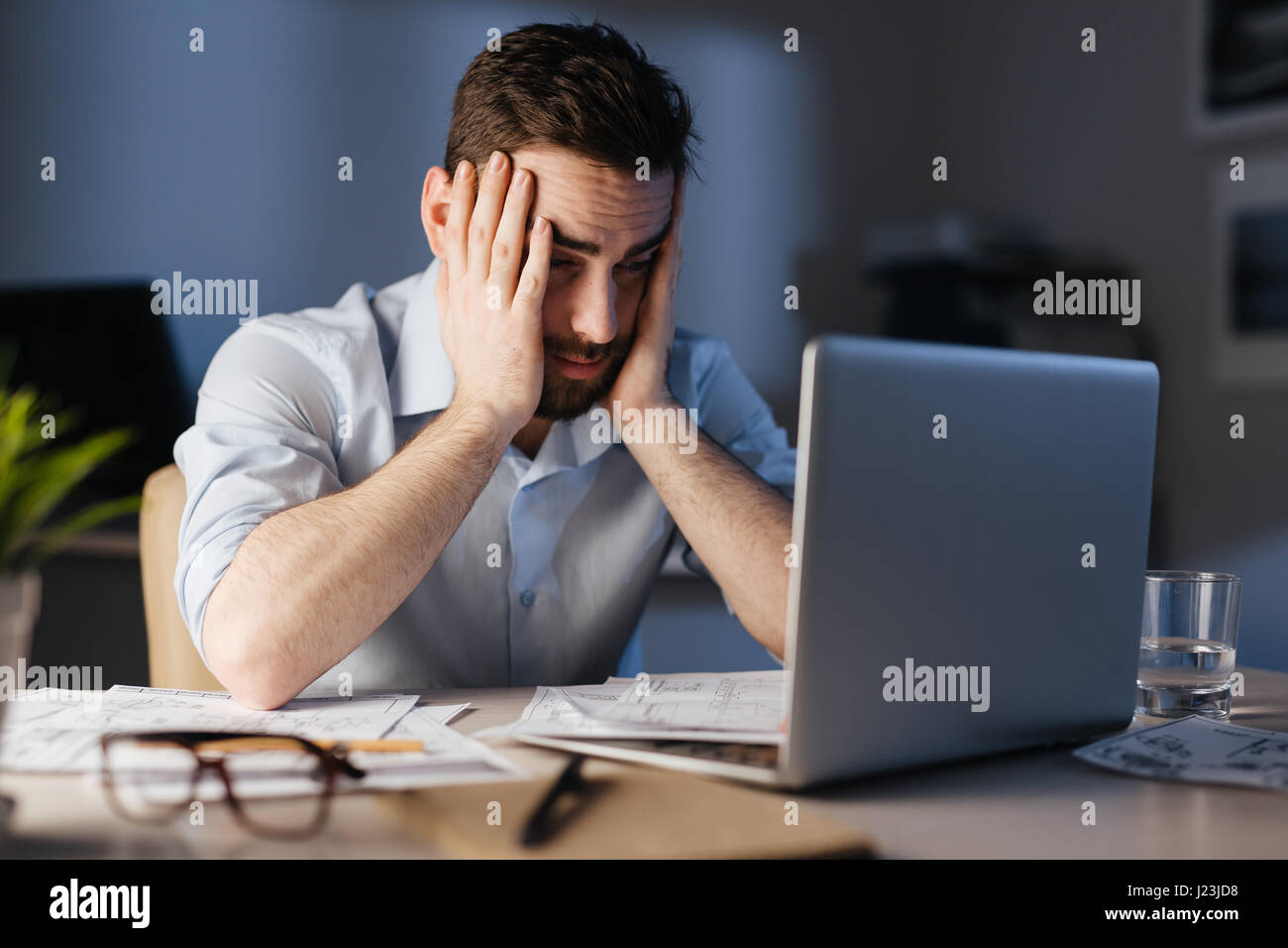 Overworked businessman sitting in front of laptop Stock Photo - Alamy