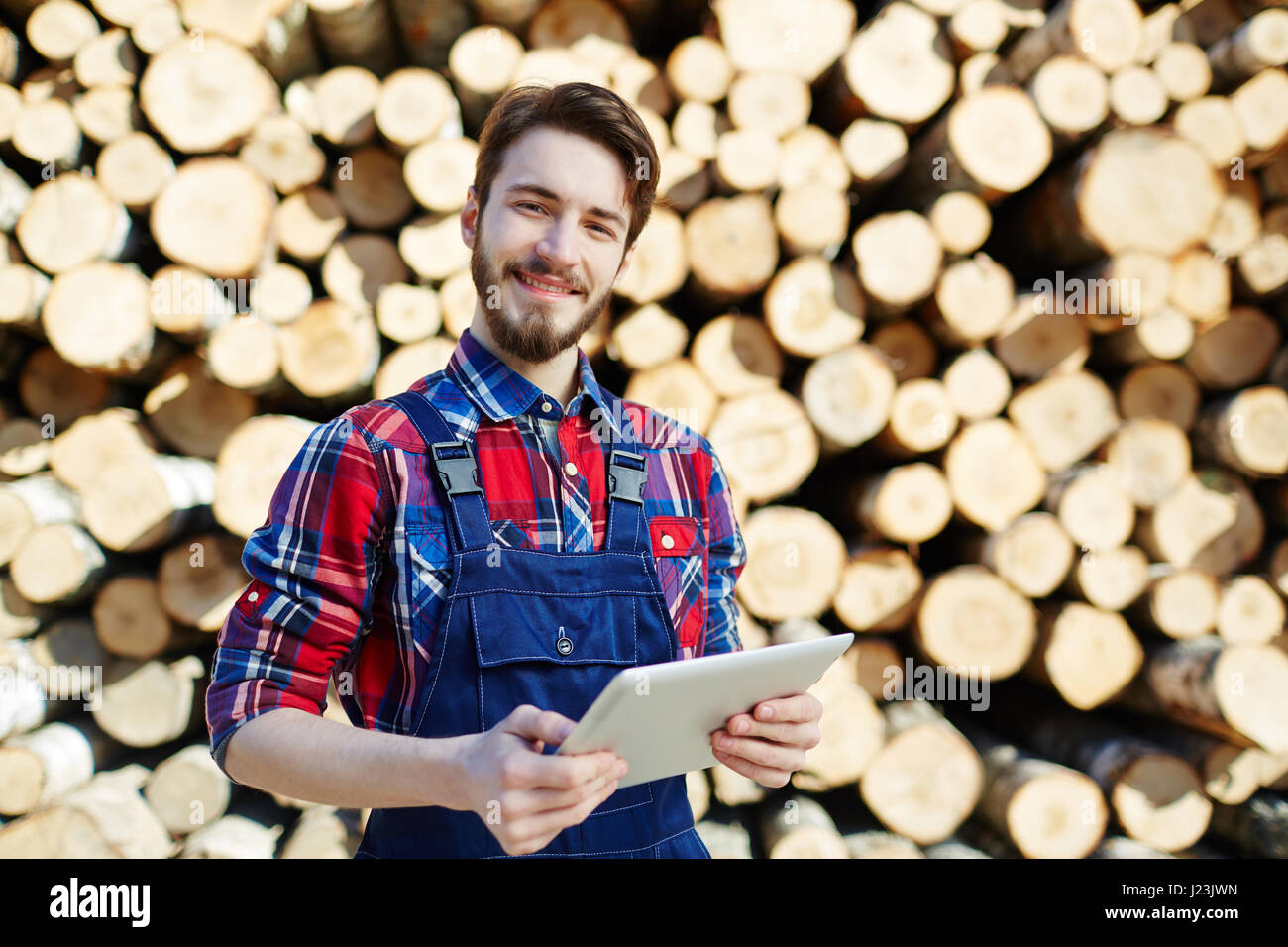 Happy young lumber with touchpad working on lumberyard Stock Photo - Alamy