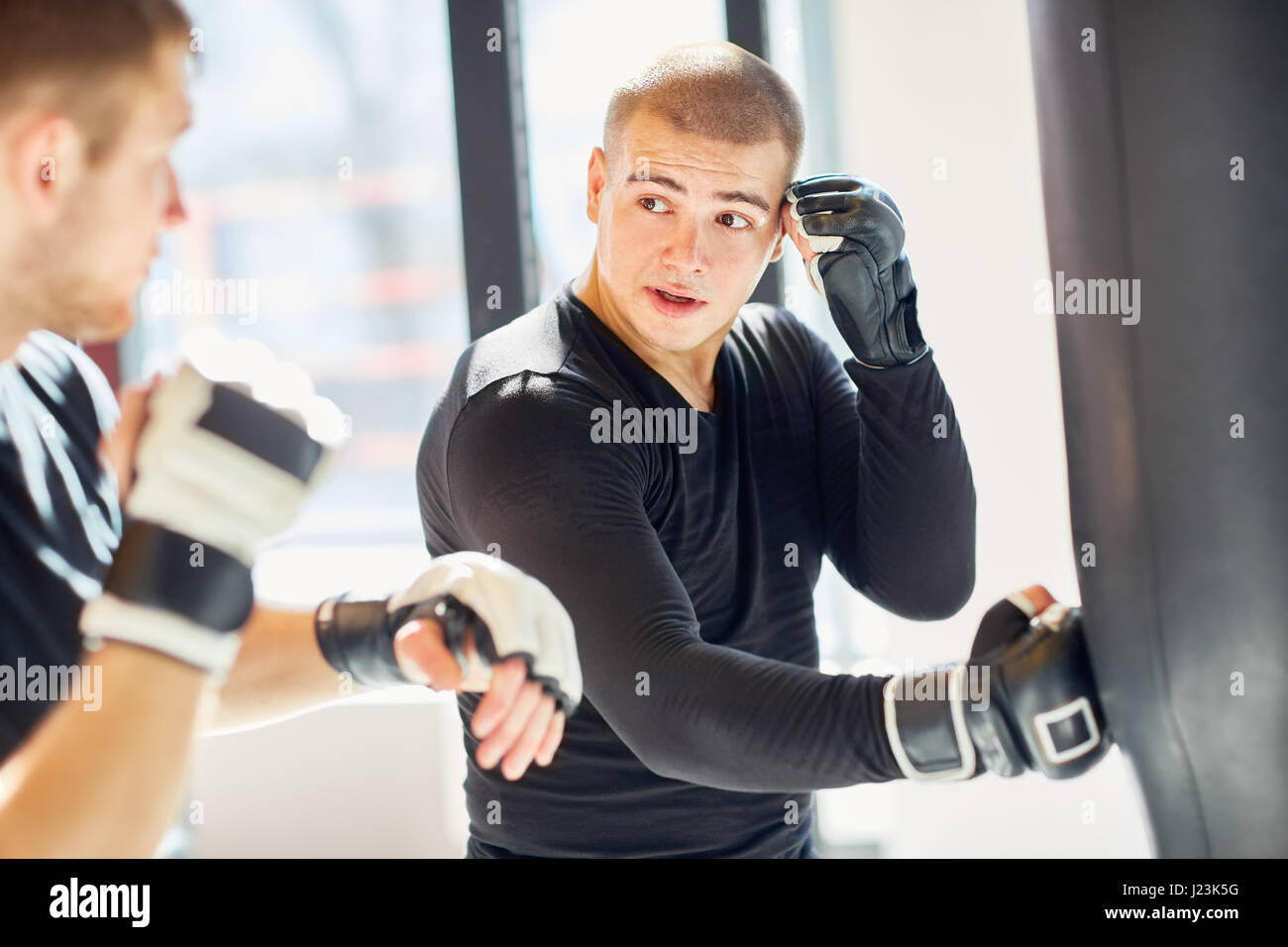 Portrait of young muscular sports man hitting punching bag during ...