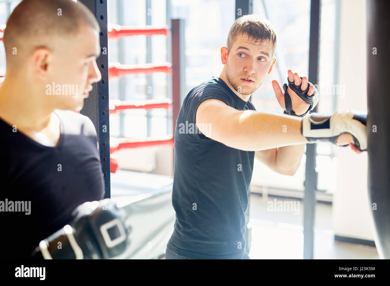 Portrait of young muscular sports man hitting punching bag during ...