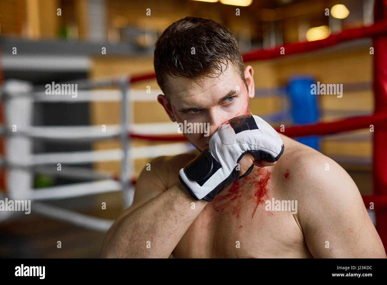 Portrait of tough muscular man wiping blood from face after finishing ...