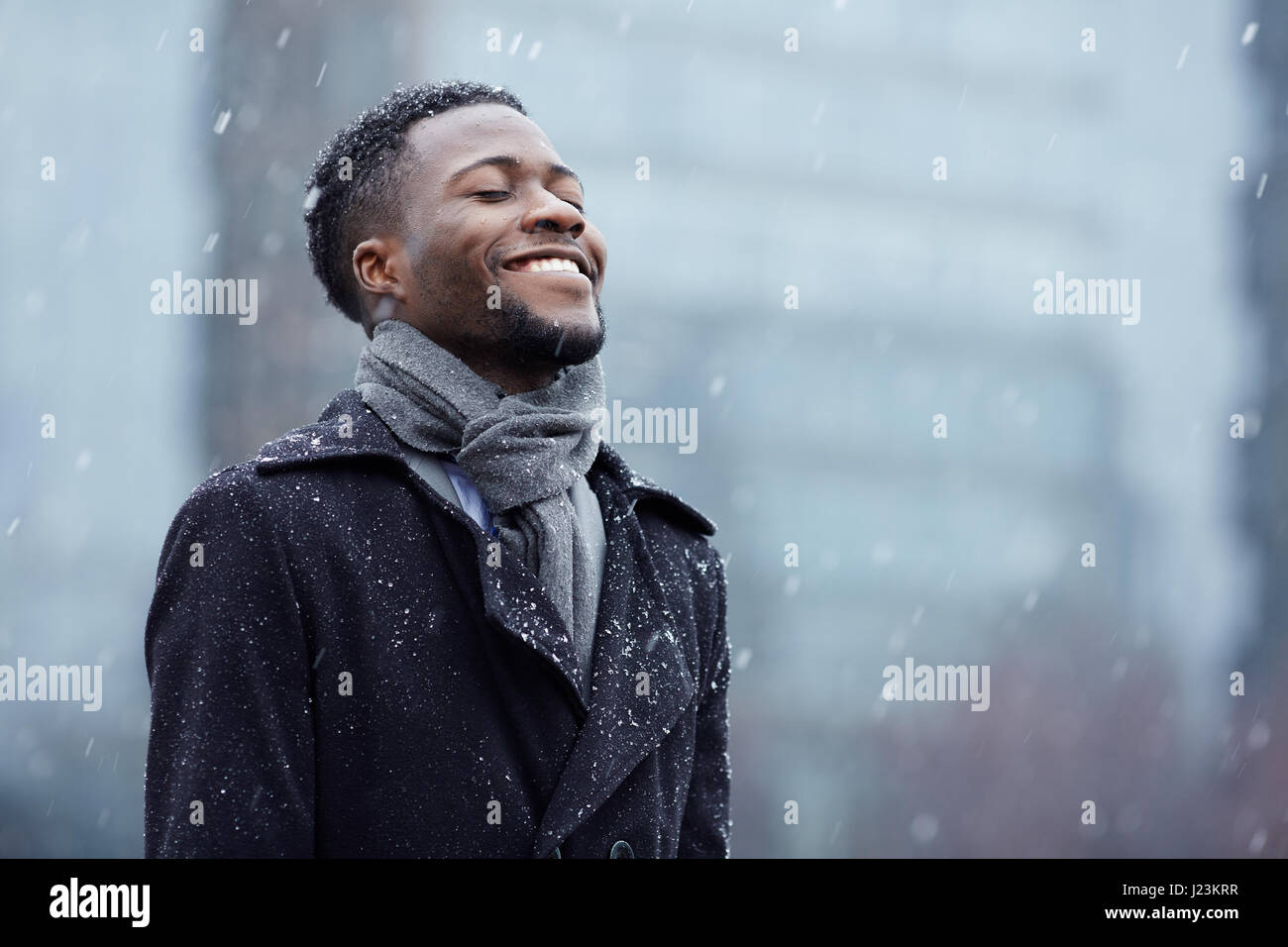 Cheerful man enjoying snowflakes falling from upwards Stock Photo - Alamy