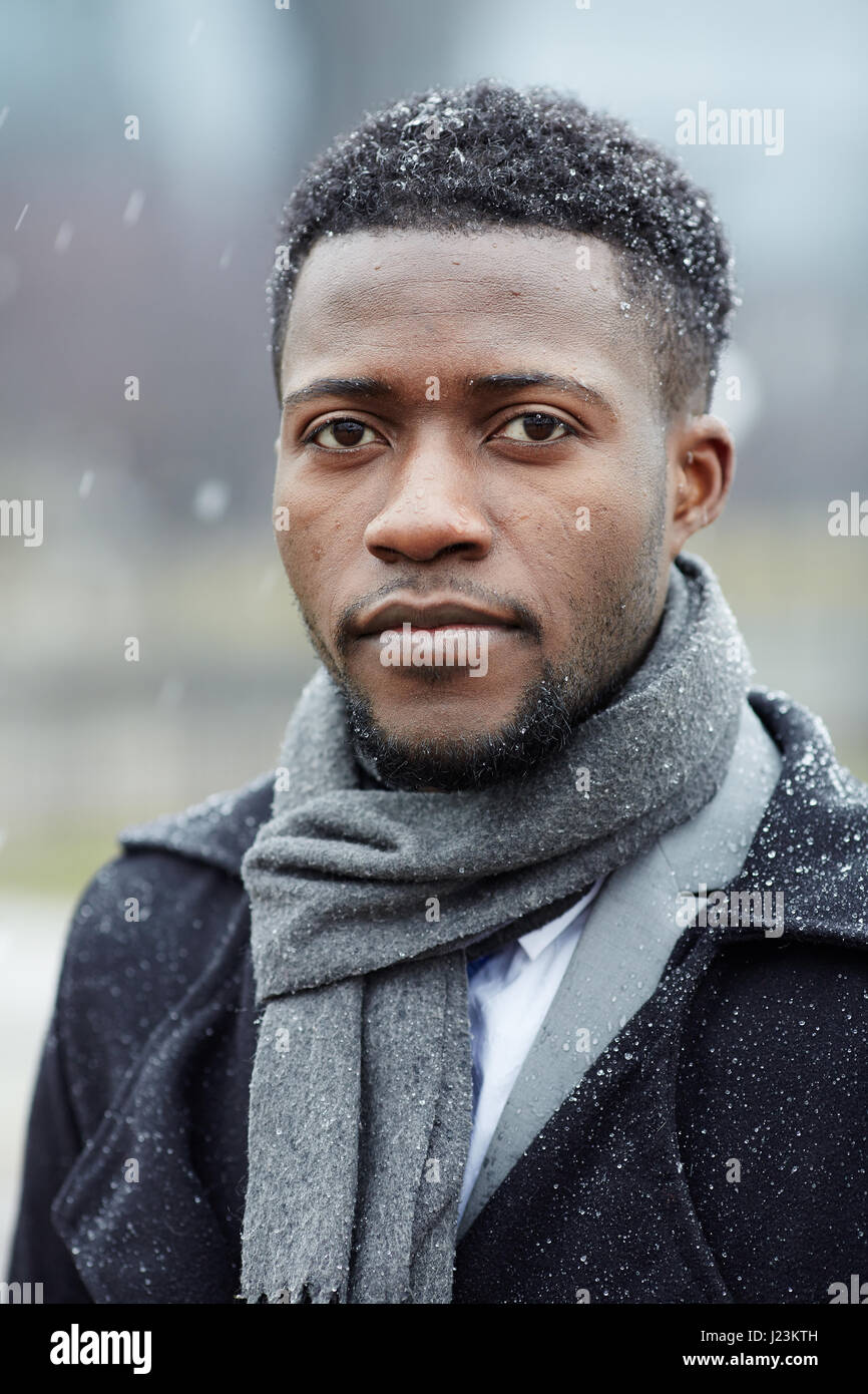 African man with grey scarf on neck looking at camera in snowfall Stock ...