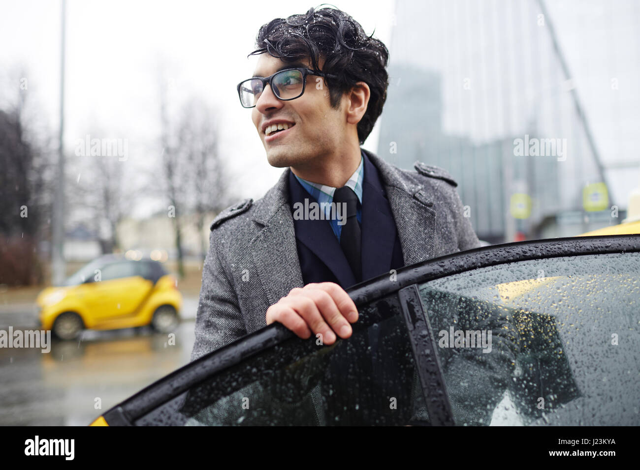 Successful man leaving taxi cab on rainy day Stock Photo - Alamy
