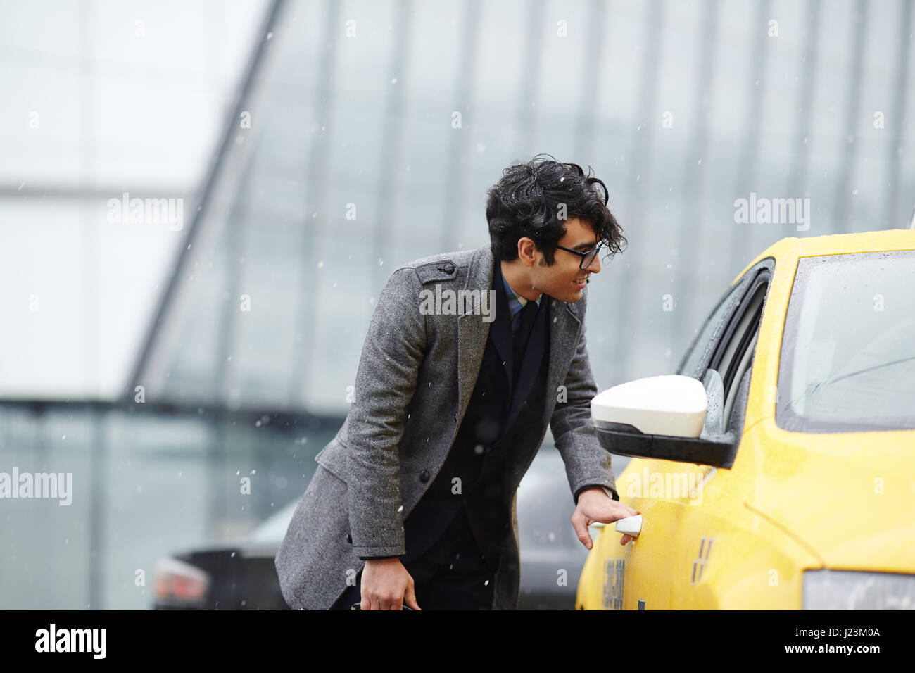 Businessman catching taxi on rainy day Stock Photo - Alamy