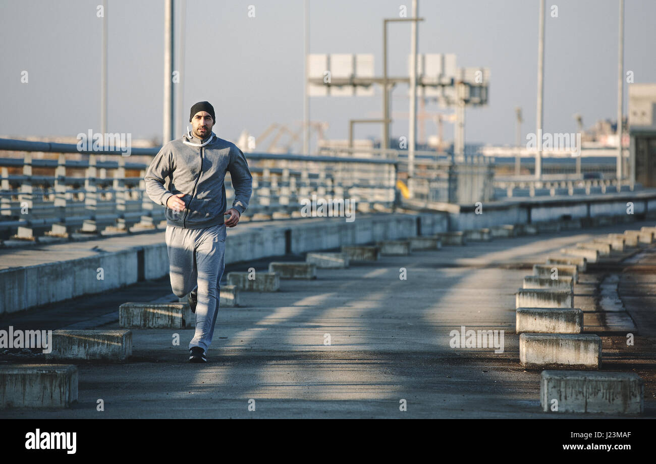 Handsome young athlete man working out. Runner jogging over bridge road ...