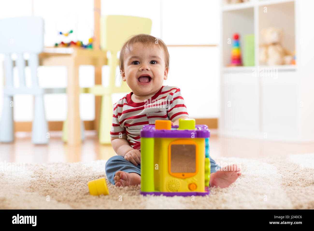 Baby boy playing with colorful toys at home. Happy seven months old ...