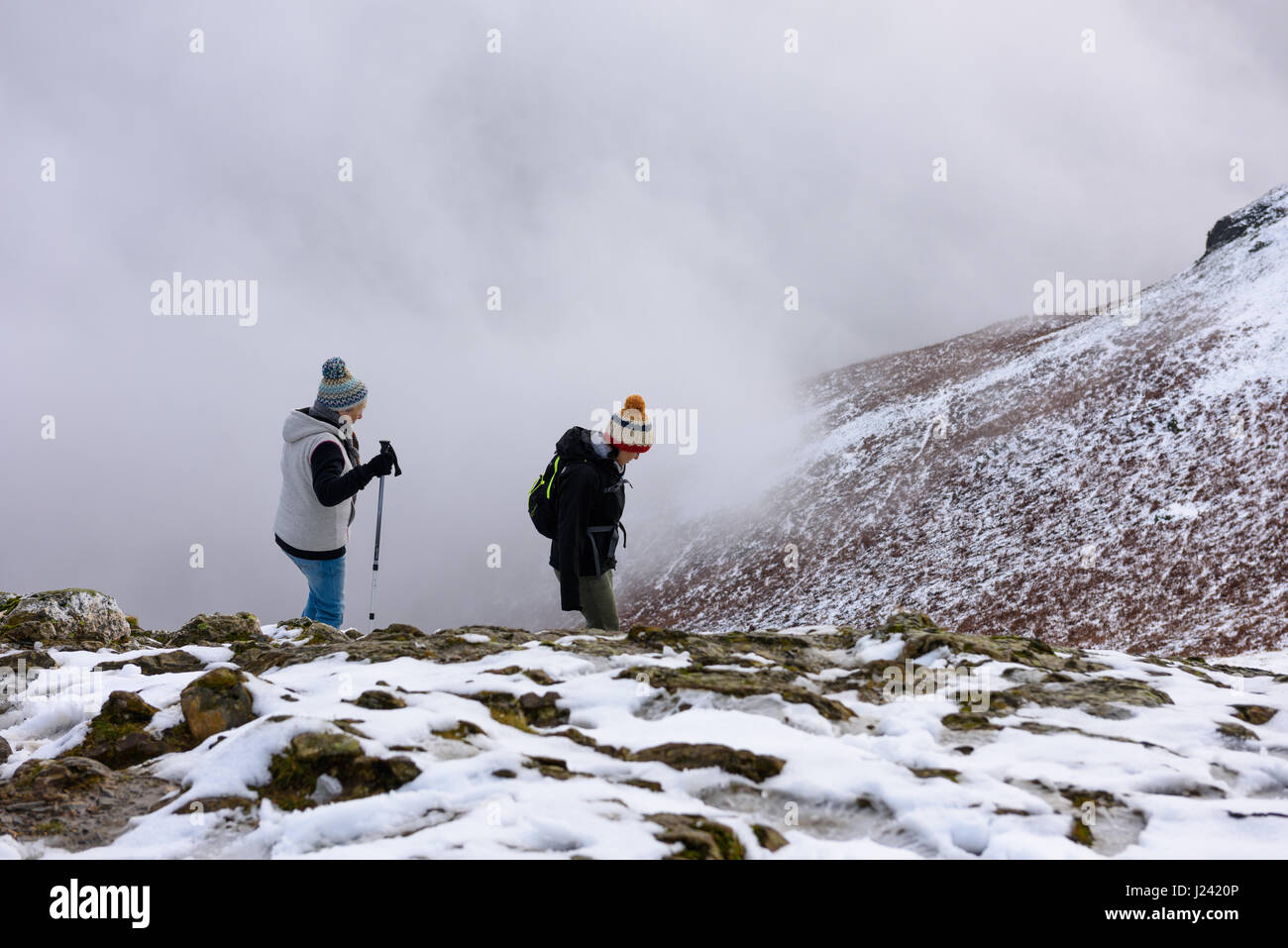 Fell walkers on Cat Bells in late autumn snow. Lake District National ...