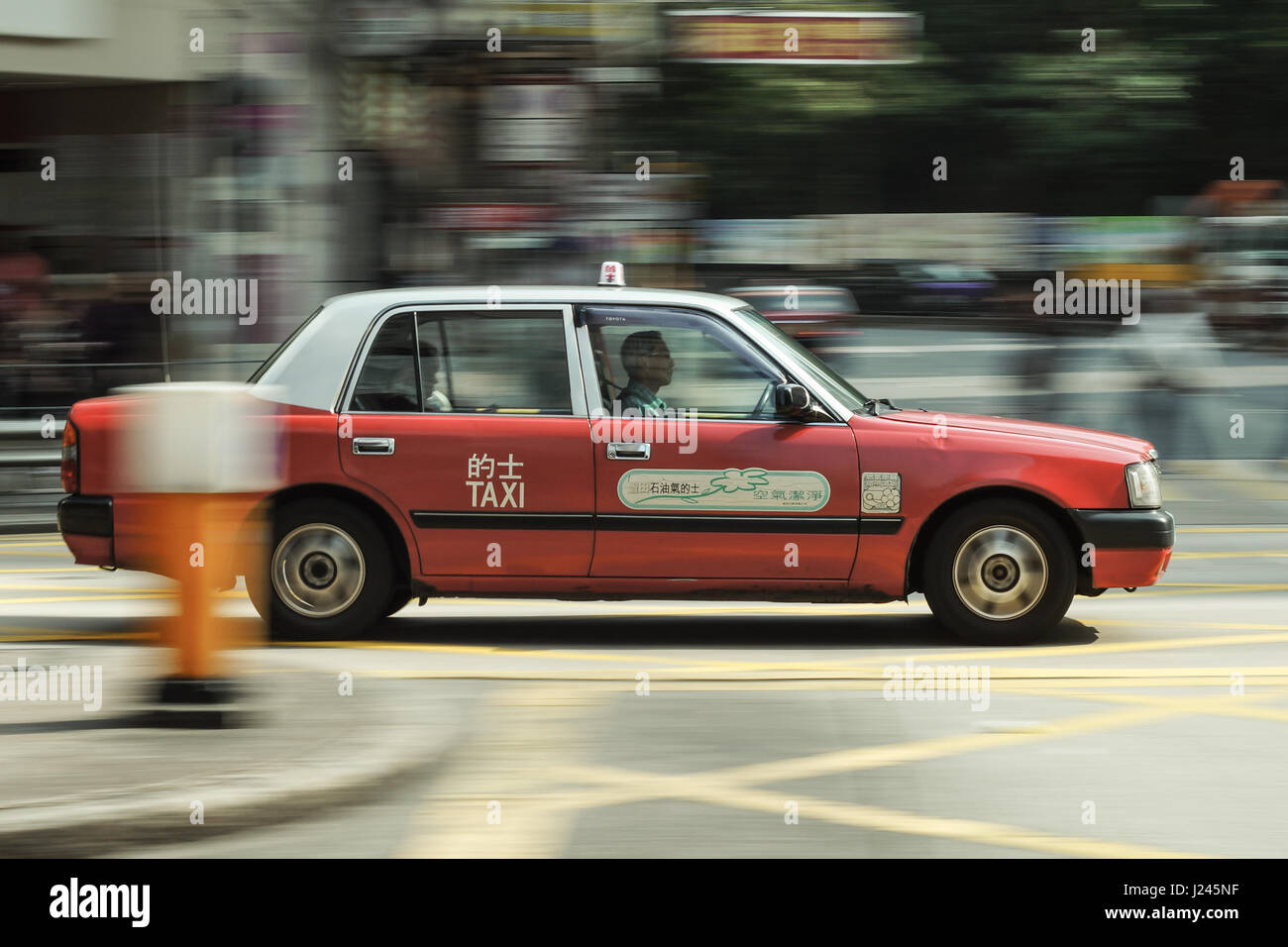 An iconic red taxi speeds along Nathan Road in the city's Kowloon area ...