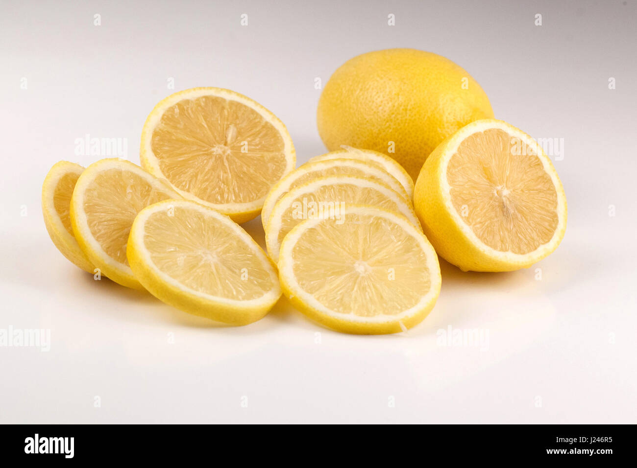 Few cut into slices lemons placed on a white table Stock Photo - Alamy