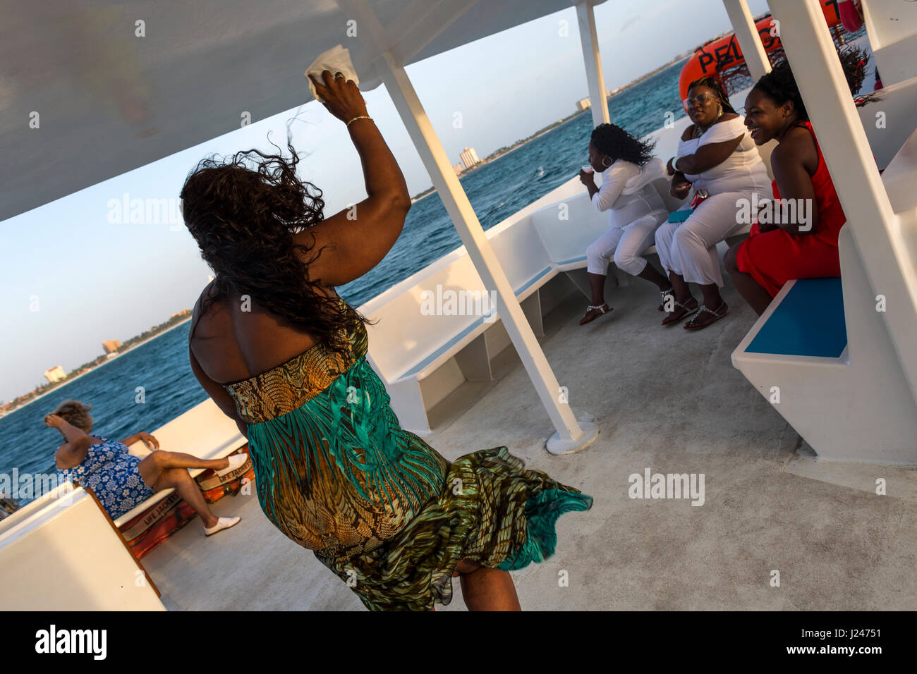 Tourists dancing and having fun on a sea-going catamaran at sunset off ...
