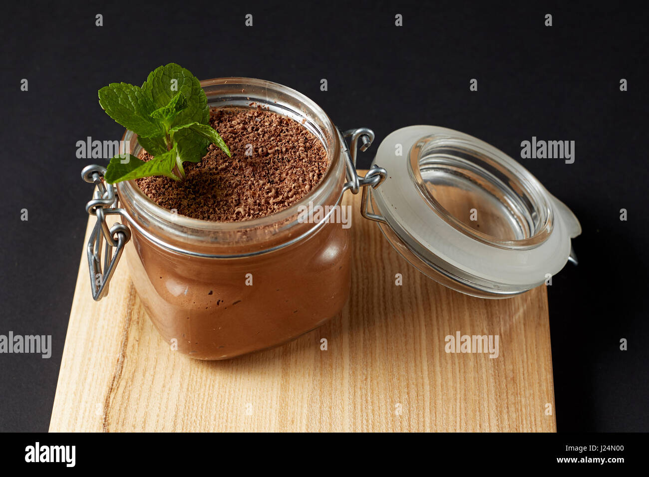 chocolate mousse with mint in a glass jar on a rustic wooden table ...