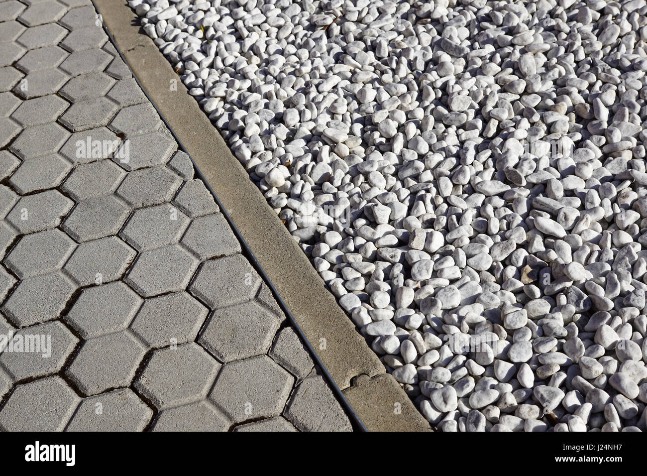 Grey colored round stones next to a concrete curb Stock Photo - Alamy