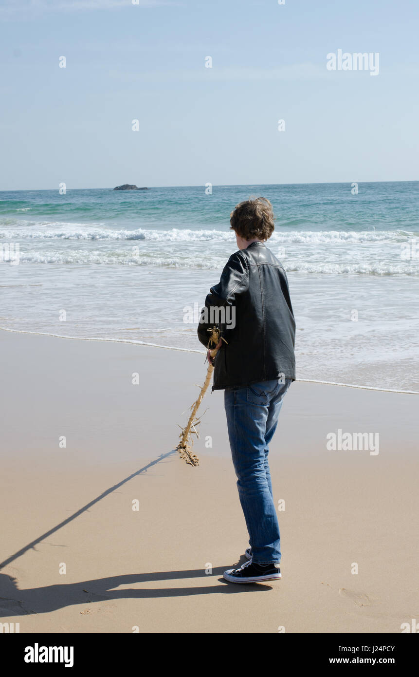 teenage boy drawing a line in the sand with a stick Stock Photo - Alamy