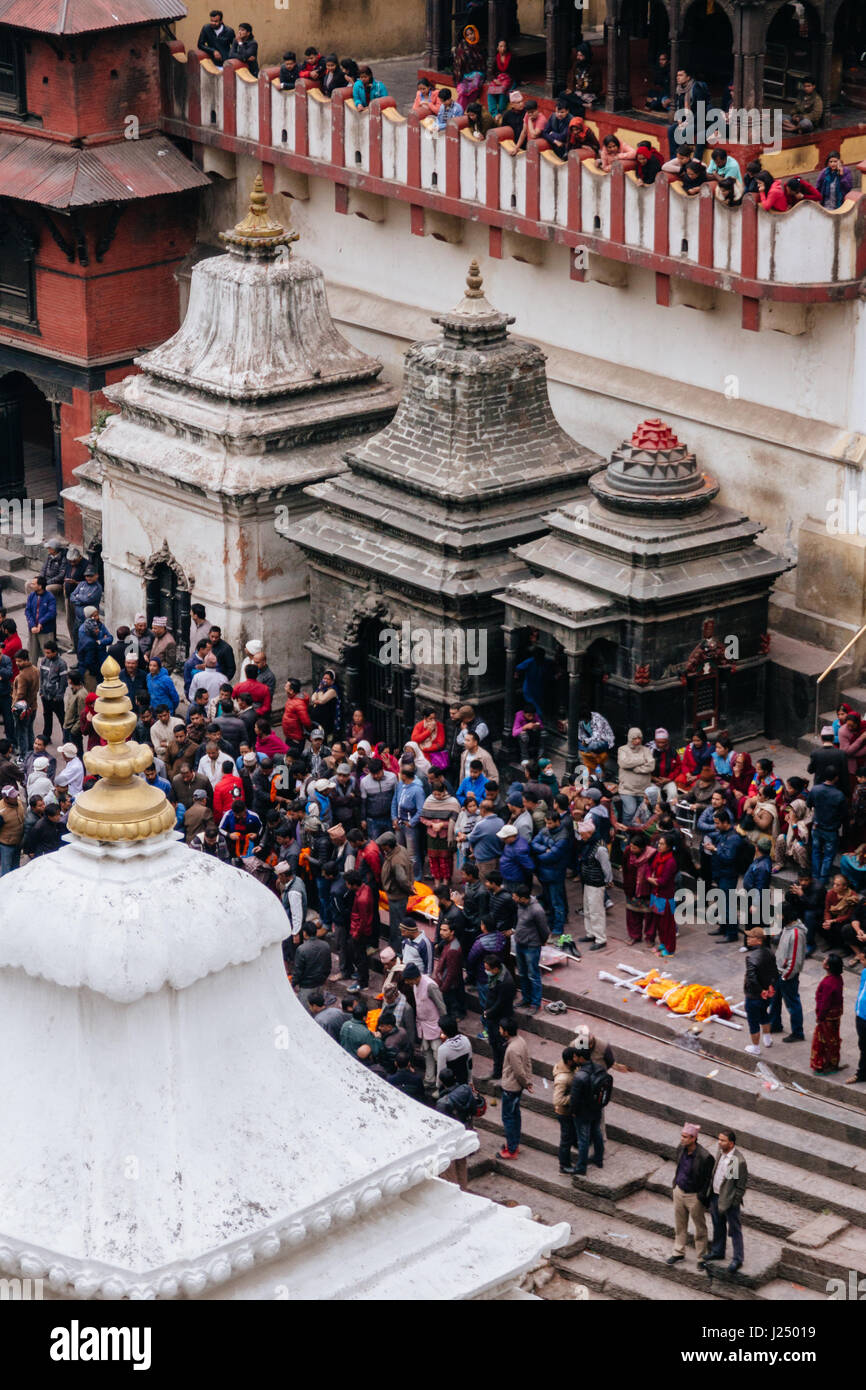 A crowd gathers around the bodies of the deceased as they are prepared ...