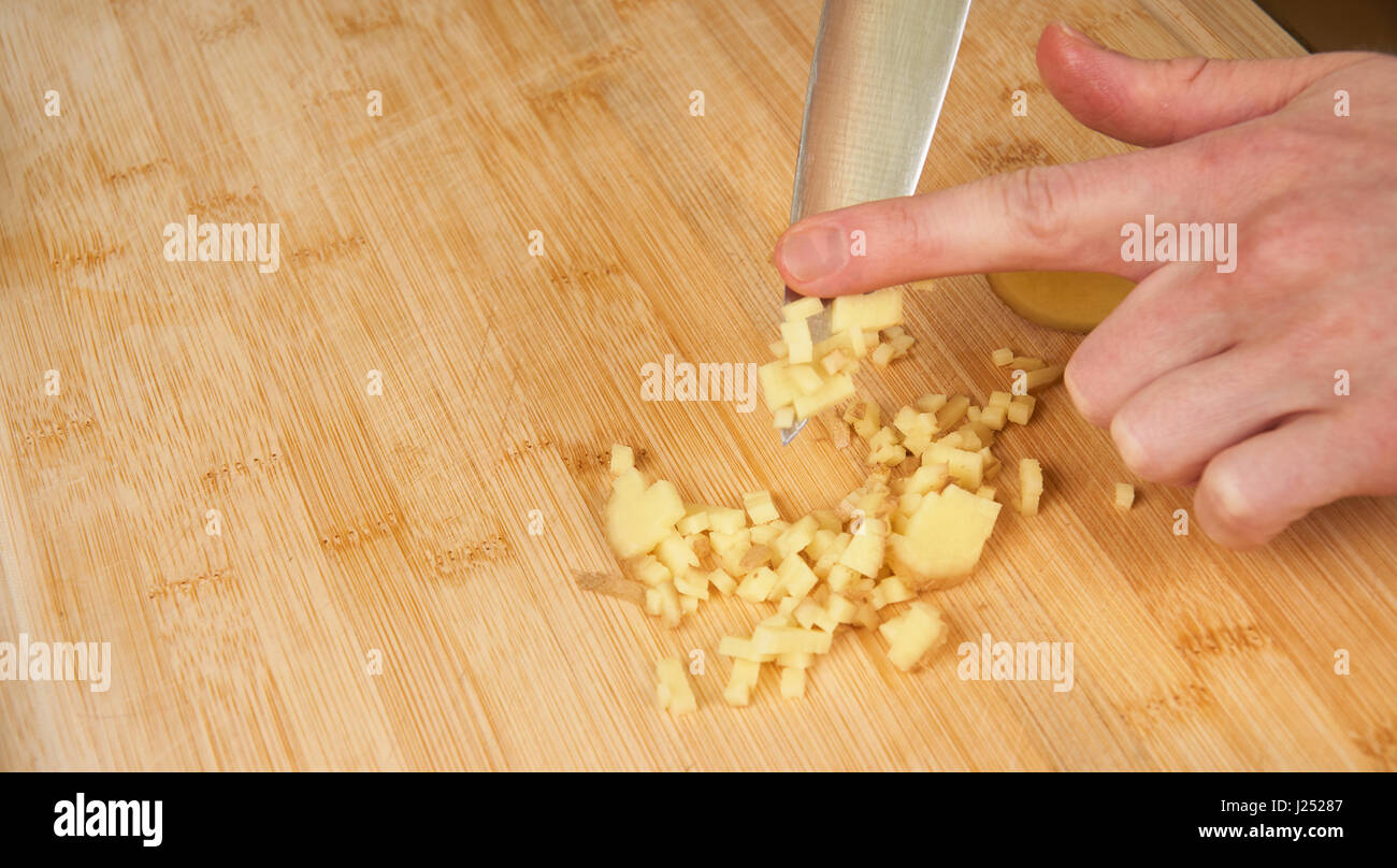 Man's hands cutting fresh garlic in the kitchen, preparing a meal for ...