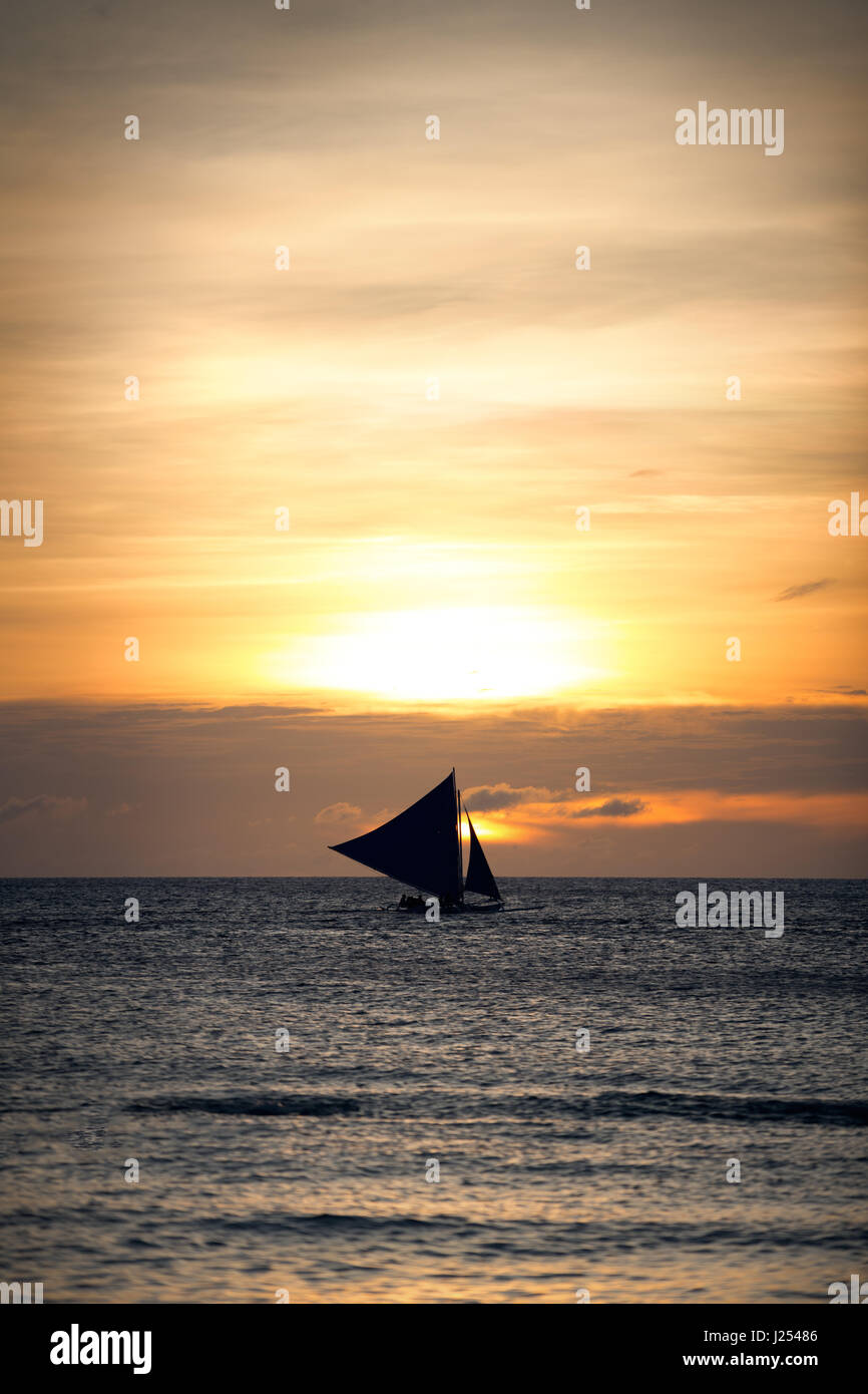 Beautiful gold sunset with a sailboat sailing Stock Photo - Alamy