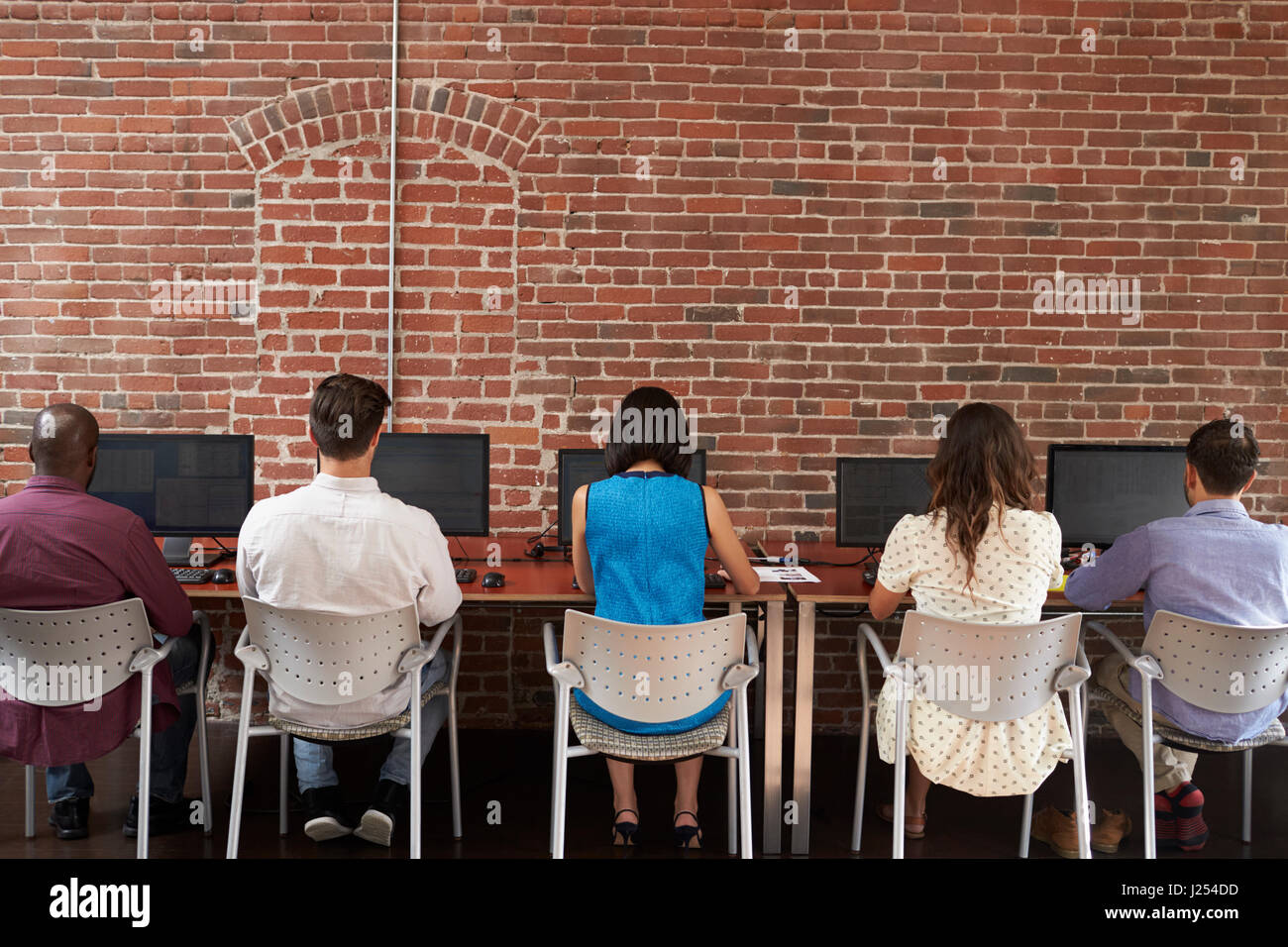 Rear View Of Staff At Desks Using Computers In Busy Office Stock Photo ...