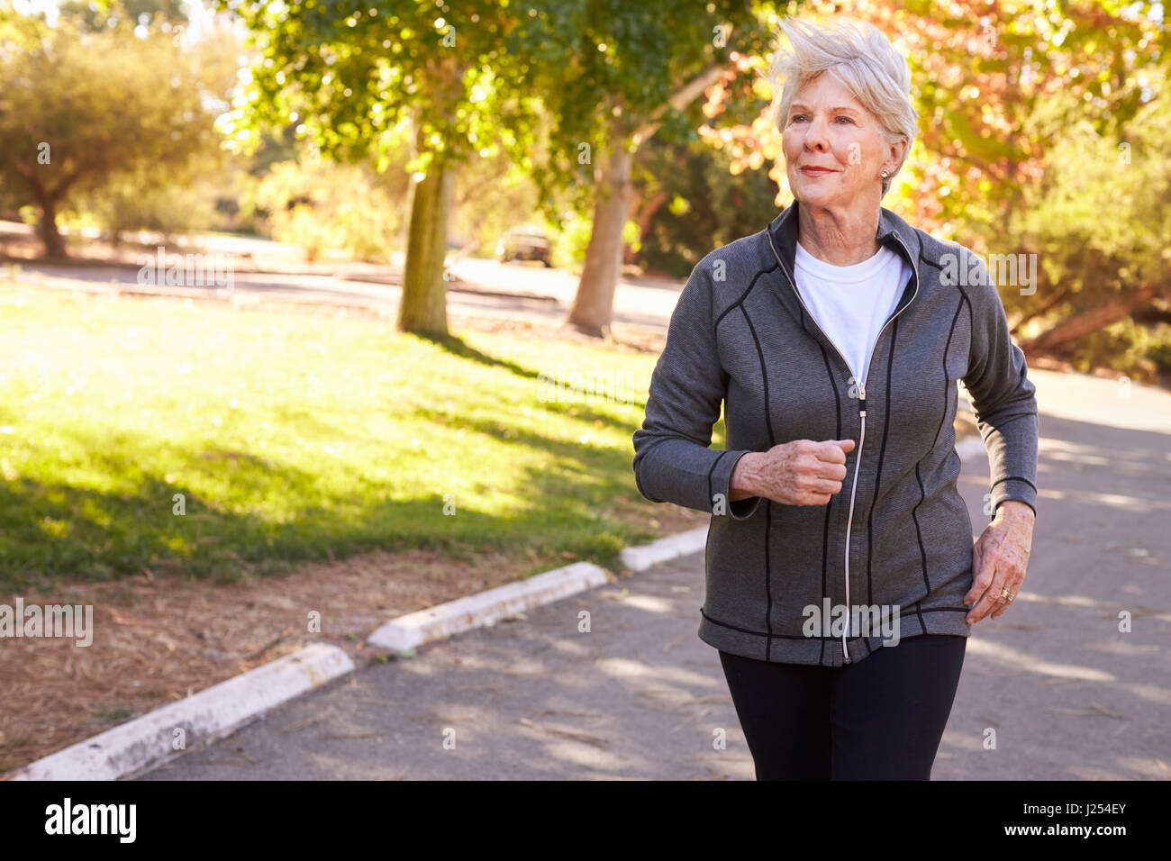 Front View Of Senior Woman Jogging Through Park Stock Photo - Alamy