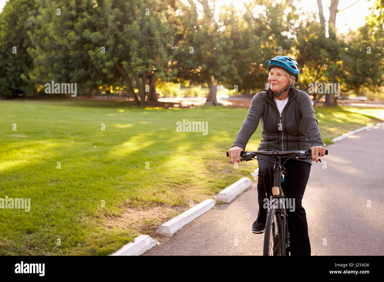 Front View Of Senior Woman Cycling Through Park Stock Photo - Alamy
